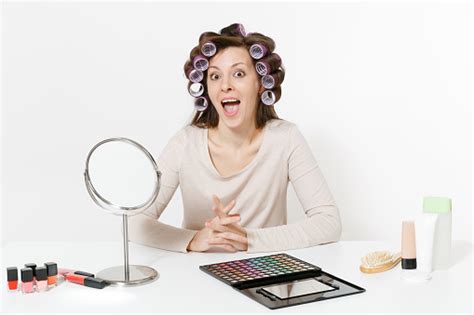 흰색 바탕에 격리 설정된 얼굴 장식 화장품으로 메이크업을 적용 하는 테이블에 앉아 머리에 컬러와 함께 재미 있는 젊은 여자 뷰티 여성 패션 라이프 스타일 개념입니다 영역