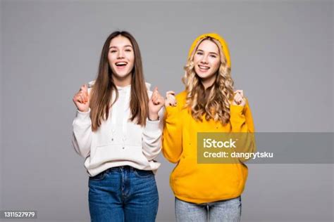 회색 배경을 축하하는 우승자 제스처를하는 두 명의 젊은 여성 2명에 대한 스톡 사진 및 기타 이미지 2명 가족 노랑 Istock