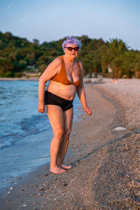 Una Anciana Con Gafas De Sol Y Traje De Baño Camina A Lo Largo De La