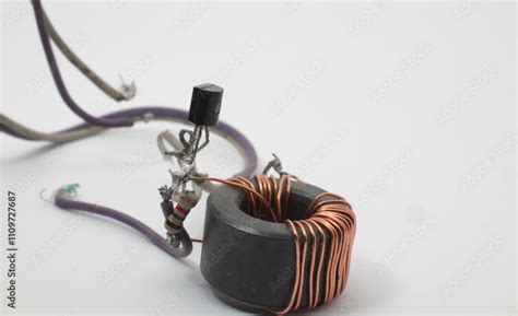 A Ferrite Core Toroid Ring With Copper Windings Connected To A Resistor And A Transistor On A