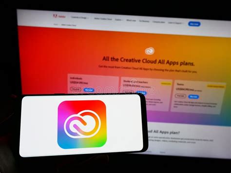 Person Holding Mobile Phone With Logo Of Software Adobe Creative Cloud On Screen In Front Of