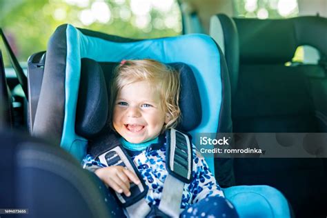파란 눈을 가진 사랑스러운 여자 아이가 카시트에 앉아 있다 가족 휴가와 조니를 떠나는 유아 교통 체증 중에 웃고 있는 행복한