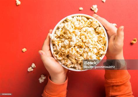 빨간색 배경에서 위에서 본 팝콘 팝콘을 먹는 아이 인간의 손 시네마 스낵 컨셉 영화와 엔터테인먼트를 감상할 수 있는 음식 텍스트의 공간을 복사 평평한 누워 Premiere에