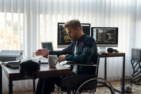 Multitasking Back View Of Young Caucasian Male Web Developer In A Wheelchair Writing Program