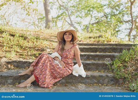 Barefoot Woman Enjoying Nature Seated On The Steps Of A Public Garden