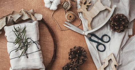 소나무 콘 순록 가위 꼬기 면이 있는 나무 테이블에 녹색 가지가 있는 린넨 패브릭으로 싸인 세련된 소박한 선물 플랫 레이 심플한 에코는 플라스틱을 무료로