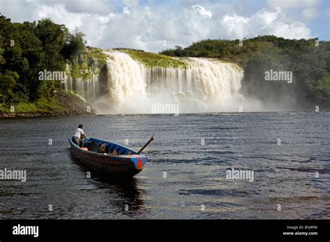 A Pemon Tribe Man While Sailing With His Boat At Canaima Lake Just In Front Of A Big Waterfall
