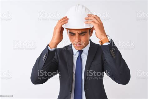 젊은 잘생긴 건축가 남자는 고립 된 흰색 배경 위에 양복과 헬멧을 착용두통 이 절망적으로 고통과 편두통 때문에 스트레스 머리에 손을 걱정하는에 대한 스톡 사진 및 기타