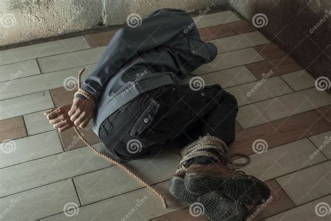 An Unrecognizable Man Is Captured In The Basement Bound By A Rope Hand