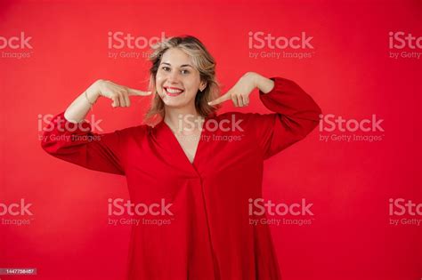 빨간 배경에 고립된 하얀 이빨을 가리키는 빨간 옷을 입은 쾌활한 젊은 여성의 초상화 아름다운 미소 치과 진료소 광고 건강한 치아 패션 및 뷰티 산업 25 29세에 대한 스톡