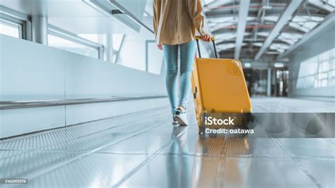현대 공항 터미널에서 노란색 여행 가방을 들고 걷는 젊은 여성 여행자 비행기 탑승구로가는 길에 여자의 뒷모습 여행 또는 휴가 여행 준비 복사 공간 20 24세에 대한 스톡