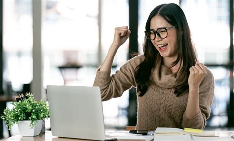 디지털 태블릿으로 사무실에 앉아있는 우아한 사업가 사무실에서 노트북에서 작업하는 동안 축하하기 위해 손을 들고 흥분 아시아 사업가 경영자에 대한 스톡 사진 및 기타 이미지