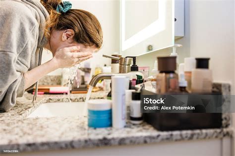 신선한 아침 스플래쉬 및 페이셜 그루밍 제품 갈색 머리의 백인 여성이 얼굴을 씻고 욕실에서 물을 튀기고 있다 흐릿한 전경에 제품 손질 20 24세에 대한 스톡 사진 및 기타