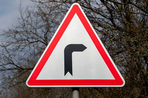 경고 표지판은 맑고 푸른 하늘 아래 벌거벗은 나무를 배경으로 우뚝 서 있는 급격한 우회전을 보여줍니다 0명에 대한 스톡 사진 및 기타 이미지 Istock