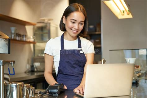 Portrait Of Young Girl Cafe Owner Looking At Her Laptop Taking Order Serving Customer In