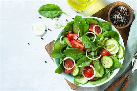 다이어트 메뉴 슬레이트 돌 또는 콘크리트 배경에 신선한 토마토 오이 양파와 시금치의 건강한 야채 샐러드 상단보기 평면 누워 배경입니다 공간을 복사합니다 0명에 대한 스톡