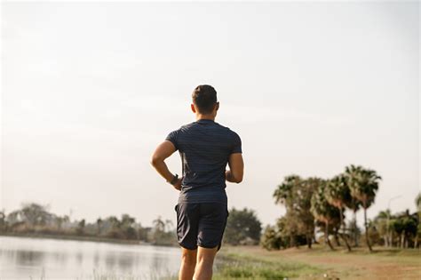 남자 운동 선수는 공원에서 아침 달리기를 즐기며 웃으며 야외에서 운동합니다 피트니스와 행복을 받아들이는 그는 건강한 생활 방식을 유지하며 자연 속에서 활기차고 긍정적인