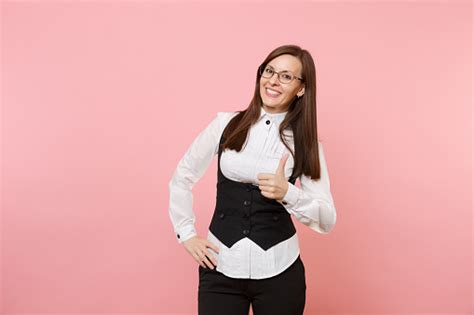 검은 양복에 젊은 즐거운 아름 다운 성공 비즈니스 여자 안경 보여주는 엄지손가락을 파스텔 핑크 배경에 고립 여자 보스입니다 성과 경력 부 개념입니다 광고에 대 한 공간을