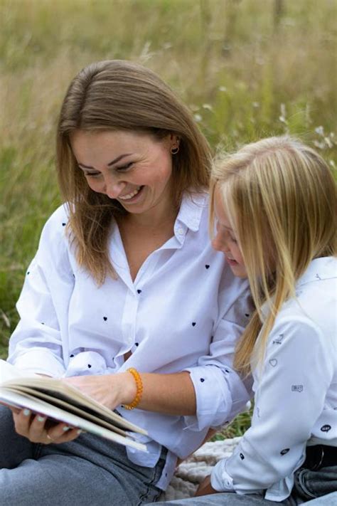 가리키는 가족 금발 기쁨 긴 머리 딸 레저 레크리에이션 미소 짓는 바람 부는 셔츠 소녀 어머니 여성 잔디 초원 쾌활한 함께에 관한 무료 스톡 사진