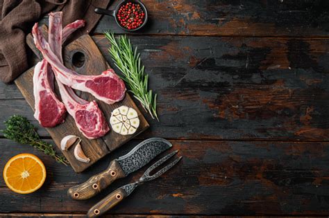 신선한 양고기 커틀릿 재료 당근 오렌지 허브 오래된 어두운 나무 테이블 배경에 유기농 고기 스테이크 상단 보기 플랫 누워 카피 스페이스와 텍스트 공간을 가진 날것에 대한