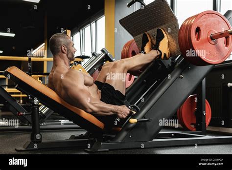 Strong And Muscular Bodybuilder Doing A Seated Leg Press Exercise In A