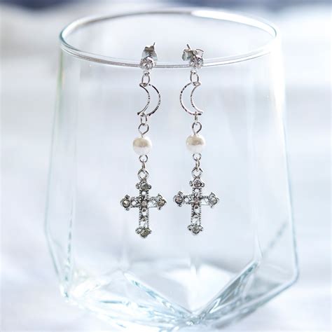 메릴 소녀의 기도 ” 고급스러우면서도 우아한 느낌의 귀걸이에요 반짝이는 스톤이 장식된 십자가 장식과 진주 달 모양의 장식이 간절함을 담아 신에게 기도하는 소녀의