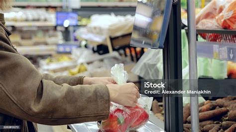 식료품점에서 형형색색의 과일과 채소에 둘러싸인 전자 저울에 담긴 비닐 봉지에 담긴 신선한 빨간 피망의 무게를 재는 쇼핑객 건강한 생활방식에 대한 스톡 사진 및 기타 이미지