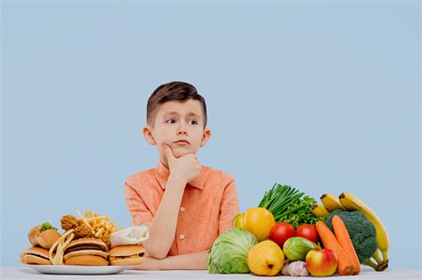 어린 소년은 당신의 선택입니다 펜서식입니다 야채 과일 또는 정크 푸드 개념 건강 음식과 패스트 푸드 파란색 배경에 격리됩니다 스튜디오 멀리 봐 고기에 대한 스톡 사진 및