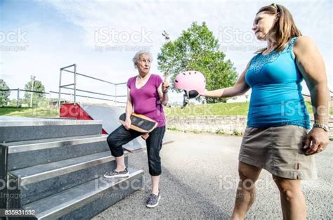 젊은 여 자가 그것을 거부 하는 고위 여자에 게 헬멧을 포기 하 고 스케이트 보드와 스케이트 진입로 계단을 올라가고 스케이트보드 타기에 대한 스톡 사진 및 기타 이미지