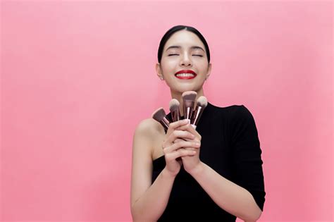 젊은 세련 된 아시아 여자 복사 공간 메이크업 브러쉬를 손에 들고 아름 다운 유행 여자 핑크 배경 위에 절연입니다 귀여운에 대한