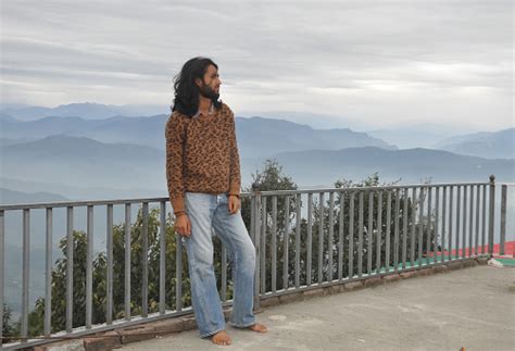 긴 머리카락과 수염을 옆으로 바라 보는 매력적인 인도 청년의 전체 길이는 배경에 산이있는 안전 장벽에 맞서 서 있습니다 20 24세에 대한 스톡 사진 및 기타 이미지