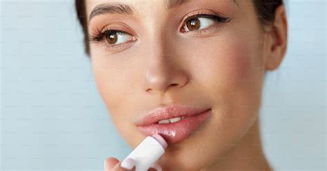 입술 보호 아름다운 얼굴 입술 가득 찬 입술 립밤을 바르는 아름다운 여자 립케어 스틱 자연스러운 화장을 한 여성 모델의 초상화 입술 스킨 케어 화장품 개념입니다