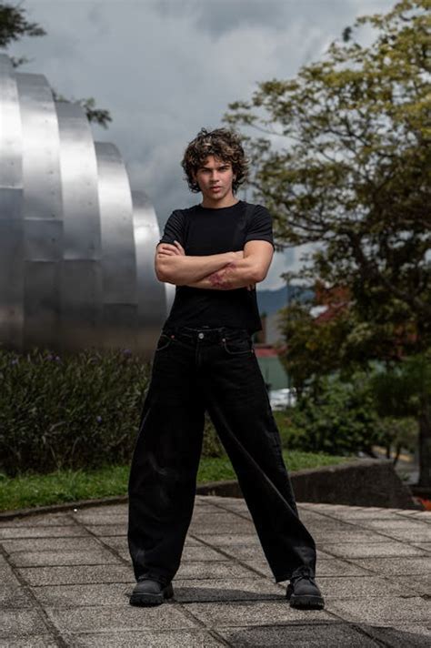 집 밖의 가로 방향 강력한 입장 개성 거리 스타일 곱슬머리 공공 장소 남자 낮 대담한 도시 경관 도시의 동적 구성 매력적인 미니멀리스트 배경