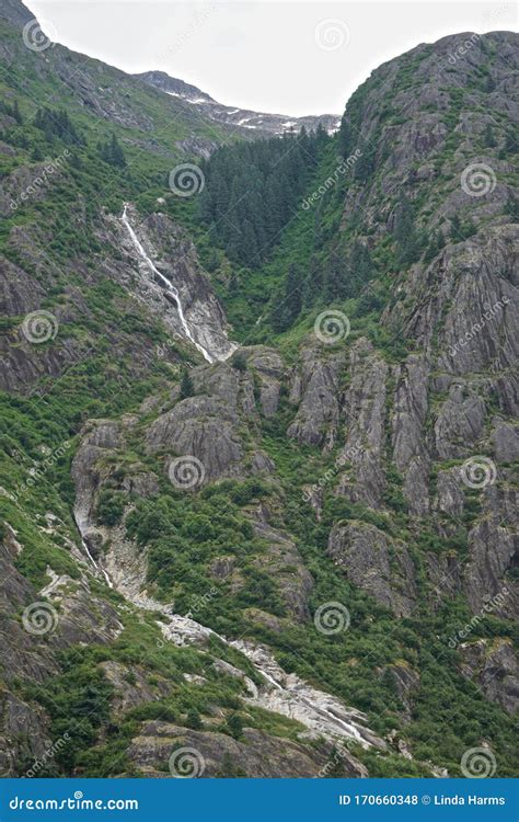 Endicott Arm Alaska A Waterfall Flows Down From A Snow Capped