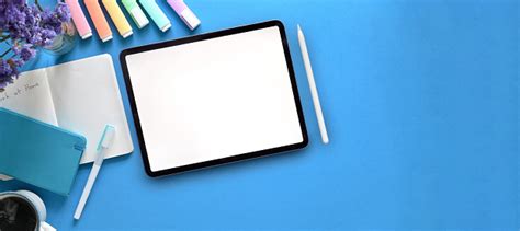 스타일러스 펜 노트 마커 펜 커피 컵과 유리 꽃병에 꽃화려한 작업 책상에 넣어 흰색 빈 화면 컴퓨터 태블릿의 상단보기 이미지 질서 정연한 다채로운 작업 공간 개념입니다