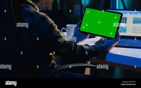 Man In Home Office Checking Statistical Financial Graphs On Laptop Crosschecking With Data On