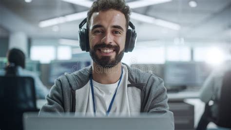 Office Portrait Of Happy It Programmer Wearing Headphones Working On