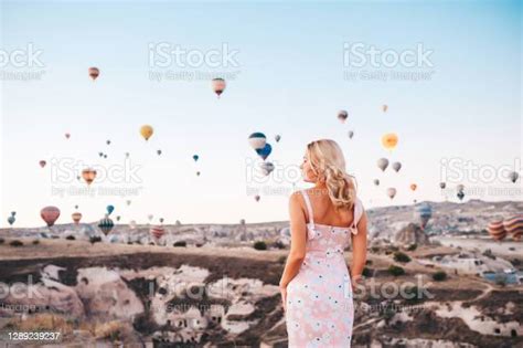 카파도키아의 일출과 풍선의 멋진 전망을 즐기는 산 꼭대기에 드레스와 모자를 쓴 젊은 여성 카파도키아에 대한 스톡 사진 및 기타 이미지 카파도키아 30 34세 걷기