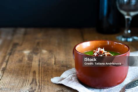 오래 된 소박한 나무 테이블의 각도에 천연 Ctoth에 갈색 찻잔에 빨간 크로 톤과 강판 된 치즈와 그린 크림 수프 병 및 유리를 디 포커 싱 복사 공간이 있는 가로입니다