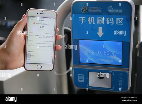 A Passenger Scans A QR Code Of The Electronic Bus Card On Her Smartphone To Pay For Bus Fees On