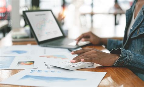 그녀의 책상 사무실에서 문서를 작업하고 비즈니스 그래프 차트를 분석하고 재무 및 마케팅 투자를 계획하는 민족 사업가의 잘린 샷 계산기에 대한 스톡 사진 및 기타 이미지