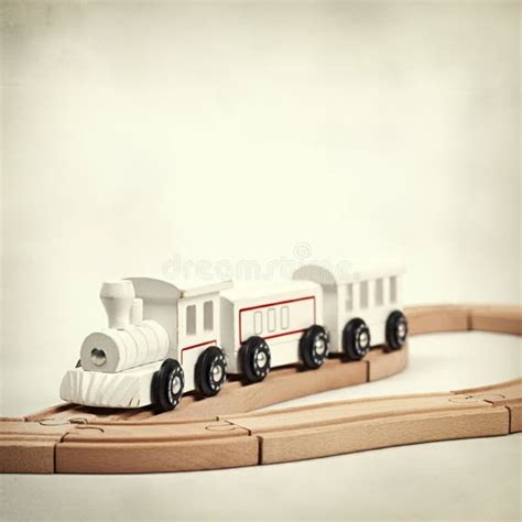 Wooden Toy Train On A Curved Wooden Track Comprising A White Engine And Two Cars Stock