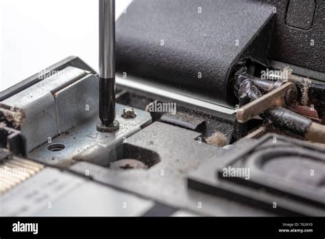 The Screwdriver Unscrews The Fastening Bolt Of The Old Dusty Processor Computer Board