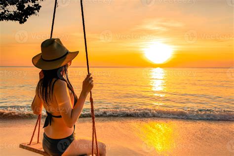 Sexy Woman Wear Bikini And Straw Hat Swing The Swings At Tropical Beach