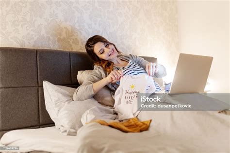 노트북을 통해 영상 통화를 데 아름 다운 갈색 머리 웃 고 여 자가 보여주는 아기 의류 그녀 구입 저녁 시간입니다 가정 생활에 대한 스톡 사진 및 기타 이미지 Istock