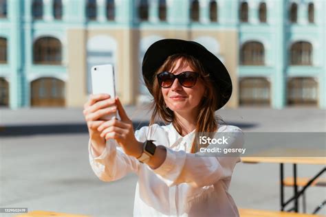 여름에 카페에 앉아 스마트폰으로 사진을 찍는 동안 모자와 선글라스를 착용한 백인 소녀 30 34세에 대한 스톡 사진 및 기타 이미지 30 34세 Brand Name