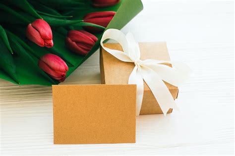 녹색 종이 선물 상자와 흰색 나무 바탕에 텍스트에 대 한 공간을 가진 공예 카드에 아름 다운 빨간 튤립 꽃다발 행복 한 어머니의 날입니다 흰색 나무에 분홍색 튤립 인사말