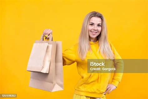 노란 배경에 고립 된 노란색 스포츠 정장에 종이 에코 가방을 가진 젊은 예쁜 백인 금발 여성의 초상화 미소 카메라를보고 가방에 대한 스톡 사진 및 기타 이미지 Istock