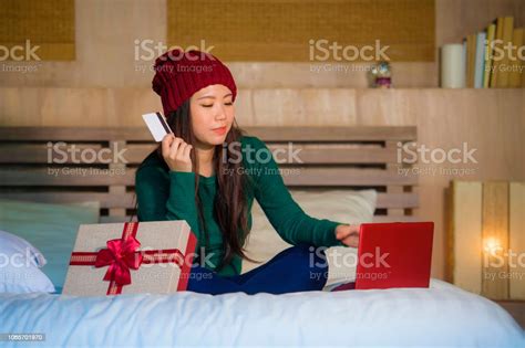 젊은 아름 답 고 행복 한 아시아 한국 여자 신용 카드와 온라인 크리스마스 쇼핑 크리스마스 선물 상자를 들고 웃 고 선물 만족 집에서 E비즈니스와 전자 상거래 개념에 침대