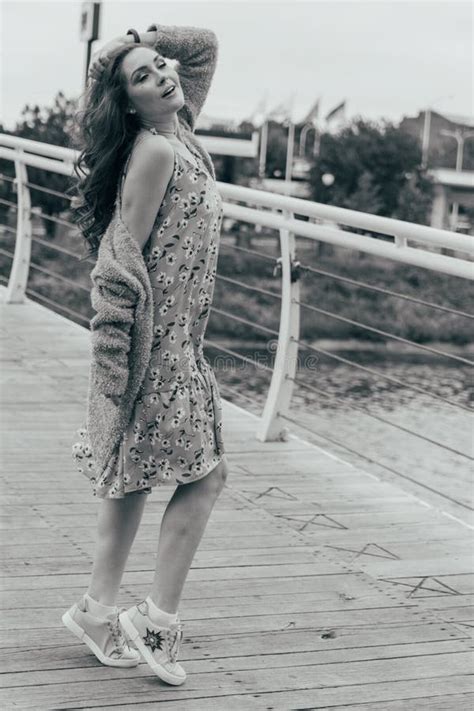 Красивая девушка стоит на мосте ветер дует в ее стороне развивая ее волосы Улыбки девушки